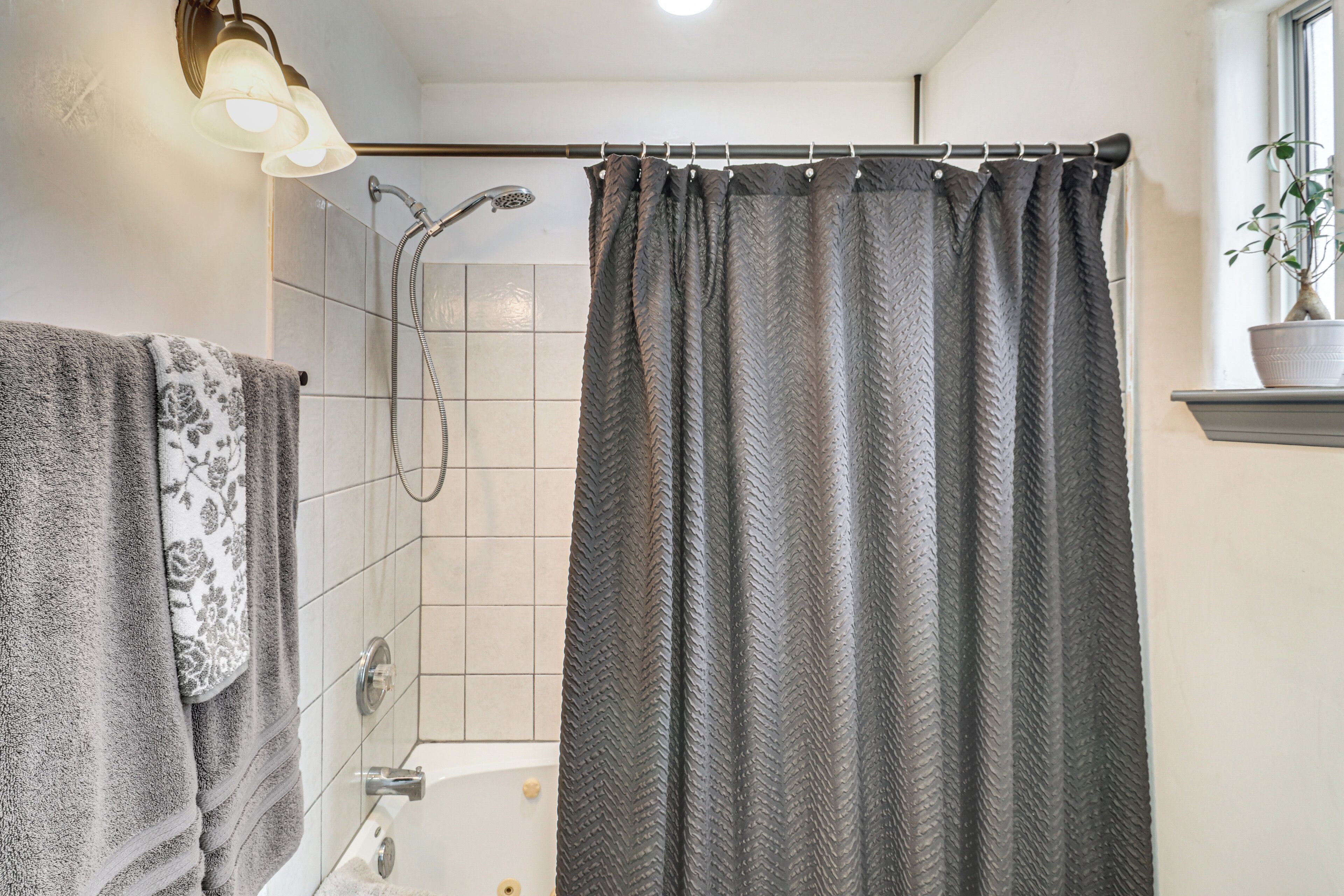 Um banheiro com chuveiro, banheira e um porta-toalhas com toalha estampada.