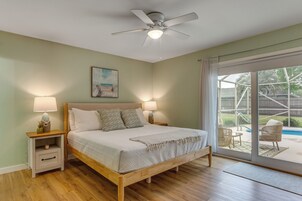 Quarto com uma cama, duas mesas de cabeceira, um ventilador de teto e uma janela grande.