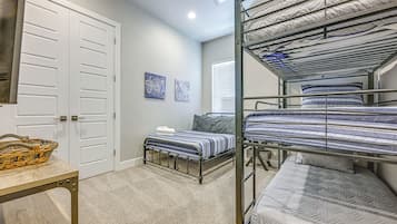 Quarto com beliches, uma porta, uma mesa pequena e duas obras de arte nas paredes.