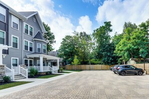Um edifício residencial de dois andares com varanda coberta e entrada de automóveis para uma área de estacionamento.