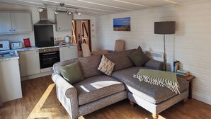 Uma sala de estar aconchegante com um sofá seccional e uma cozinha com fogão e micro-ondas.