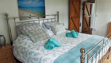 Cama bem arrumada com colcha florida, duas almofadas e um cobertor azul.