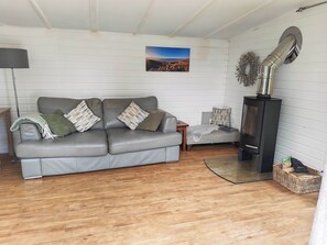 Sala de estar com sofá cinza, mesinha, lareira e um quadro na parede.