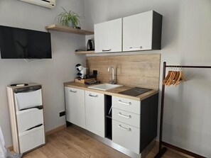 Uma cozinha moderna com armários brancos, bancada de madeira, pia e fogão preto.