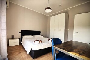 Quarto com cama, mesa de cabeceira, guarda-roupa e uma mesa de jantar.