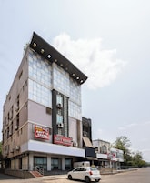 Um hotel com vários andares e fachada moderna, com grandes janelas e uma entrada destacada com degraus.