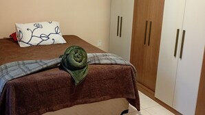 Quarto com cama, guarda-roupa e um tapete pequeno.