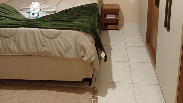 Um quarto com cama, mesa de cabeceira, guarda-roupa e uma pequena mesa.