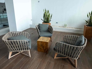 Uma área de estar moderna com móveis de vime, uma mesa de centro de madeira e plantas em vasos.