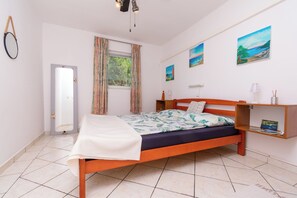 Quarto com cama, janela com cortinas, mesa de cabeceira e decoração nas paredes.