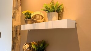 Prateleira na parede com duas plantas em vasos e uma cesta de vime.