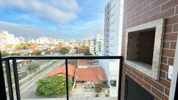 Uma varanda com vista para um horizonte urbano, incluindo edifícios residenciais e um muro de tijolos.