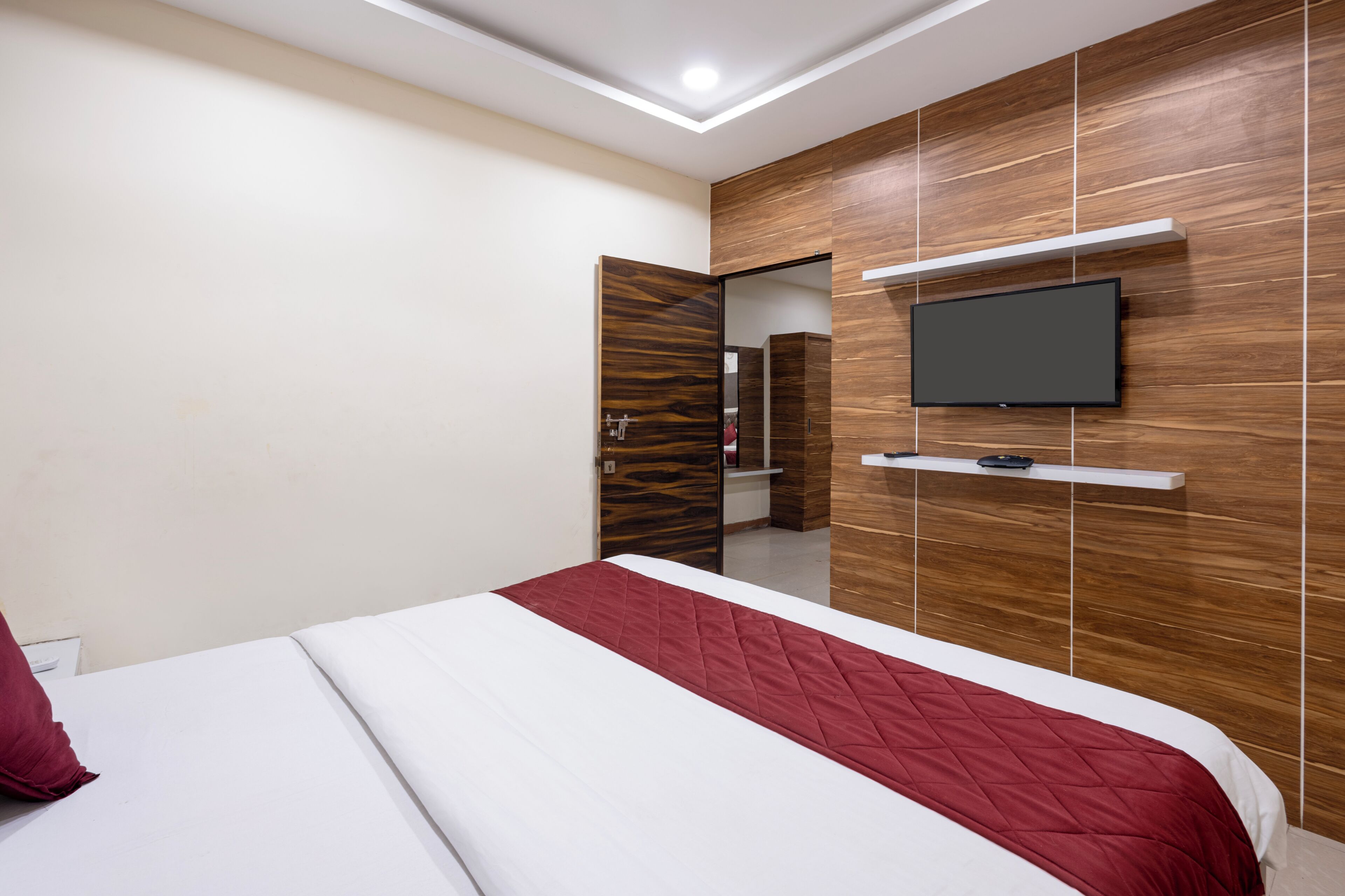 Quarto moderno com cama, televisão de tela plana na parede e armário de madeira.
