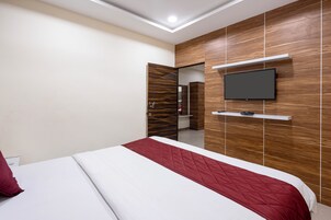 Quarto moderno com cama, televisão de tela plana na parede e armário de madeira.