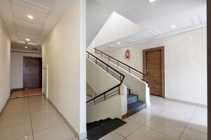Corredor que leva a uma escadaria, com um extintor fixado na parede.