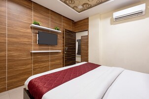 Quarto moderno com uma cama grande, televisão montada e guarda-roupa embutido.