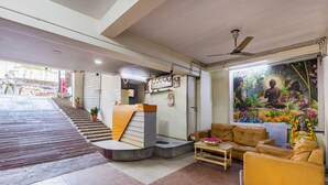 Um saguão de hotel com escadaria, área de estar e um mural.