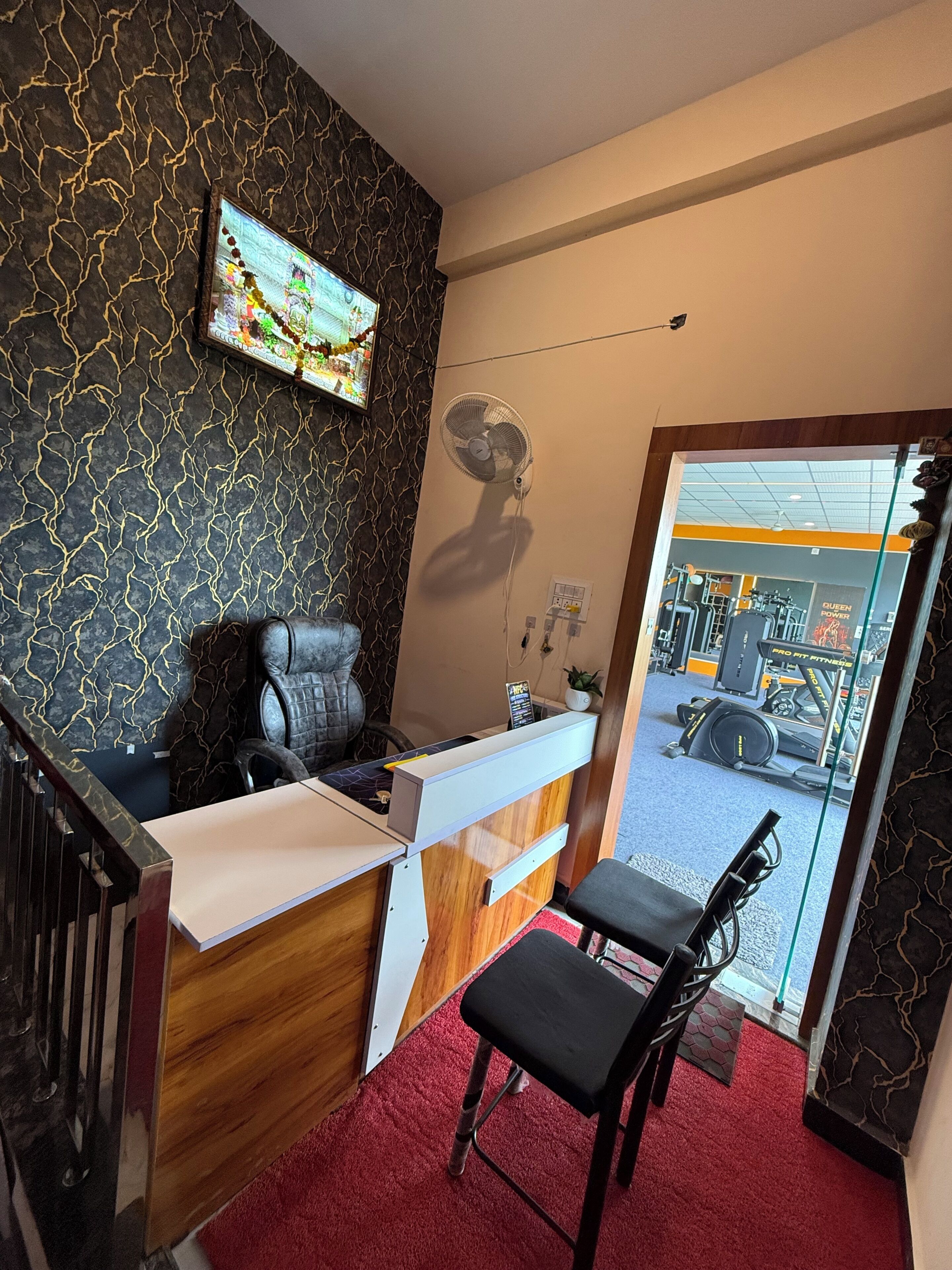 Quarto com escrivaninha, cadeira e televisão fixada na parede.