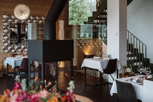 Interior de restaurante com mesas, cadeiras, lareira e escada.
