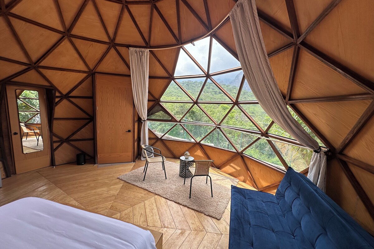 Quarto com uma janela grande, cama, cadeira e uma pequena mesa.
