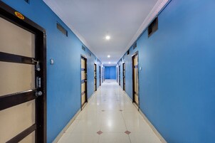 Um corredor de hotel com paredes azuis, portas numeradas e chão de azulejos.