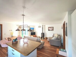 Uma sala ampla com uma mesa de jantar de madeira, um sofá e uma televisão.