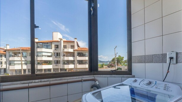 Quarto com uma janela grande, máquina de lavar e paredes revestidas de azulejos.