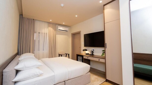 Quarto de hotel com cama, escrivaninha, televisão de tela plana, ar condicionado e espelho.