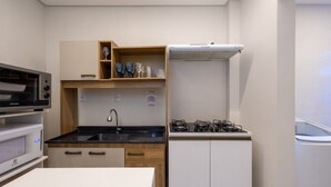 Cozinha compacta com micro-ondas, forno, pia e fogão a gás.