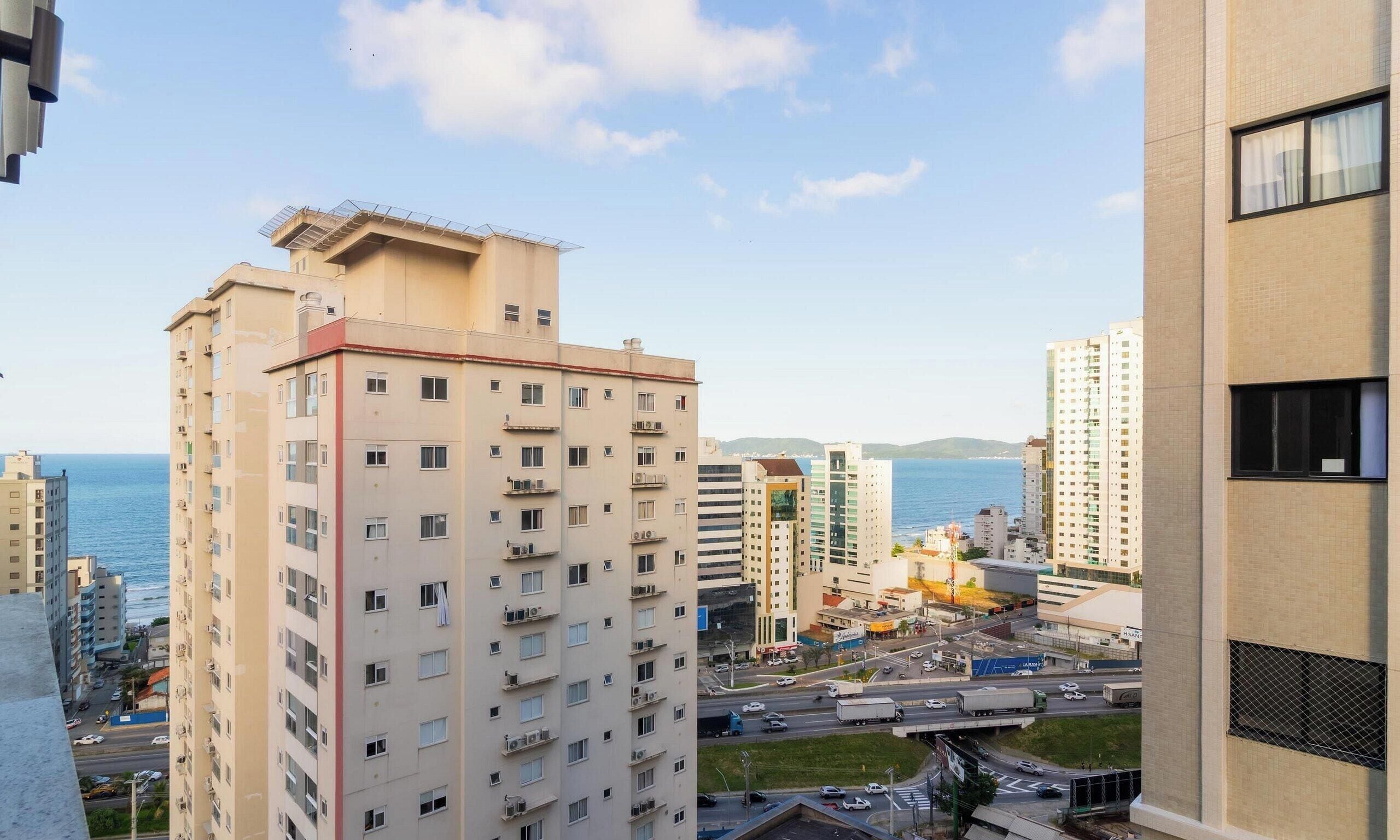 Um edifício alto com vários andares, varandas e vista para o mar.