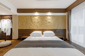 Quarto com uma cama grande, cabeceira de madeira e um guarda-roupa com roupas penduradas.
