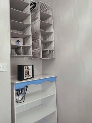 Uma unidade de armazenamento branca com vários compartimentos, uma pequena prateleira com um porta-retrato e um detalhe azul na prateleira inferior.