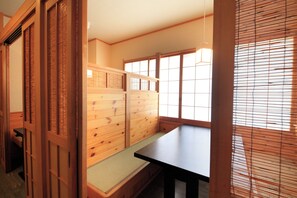 Um quarto em estilo tradicional japonês, com tatames, um banco de madeira baixo e portas deslizantes.