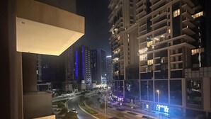 Vista noturna de uma área urbana moderna com edifícios altos, uma estrada curva e sinalização iluminada.