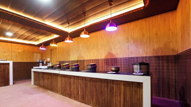 Uma área de recepção com balcão de madeira, várias máquinas de café e iluminação pendente.