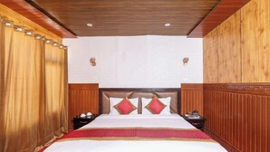 Quarto de hotel com uma cama grande, painéis de madeira e tapete vermelho.