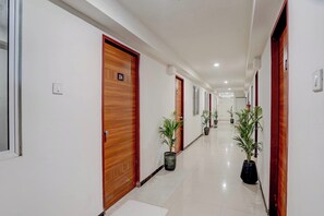 Corredor de hotel com portas de madeira, placas de número de quarto e plantas em vasos.