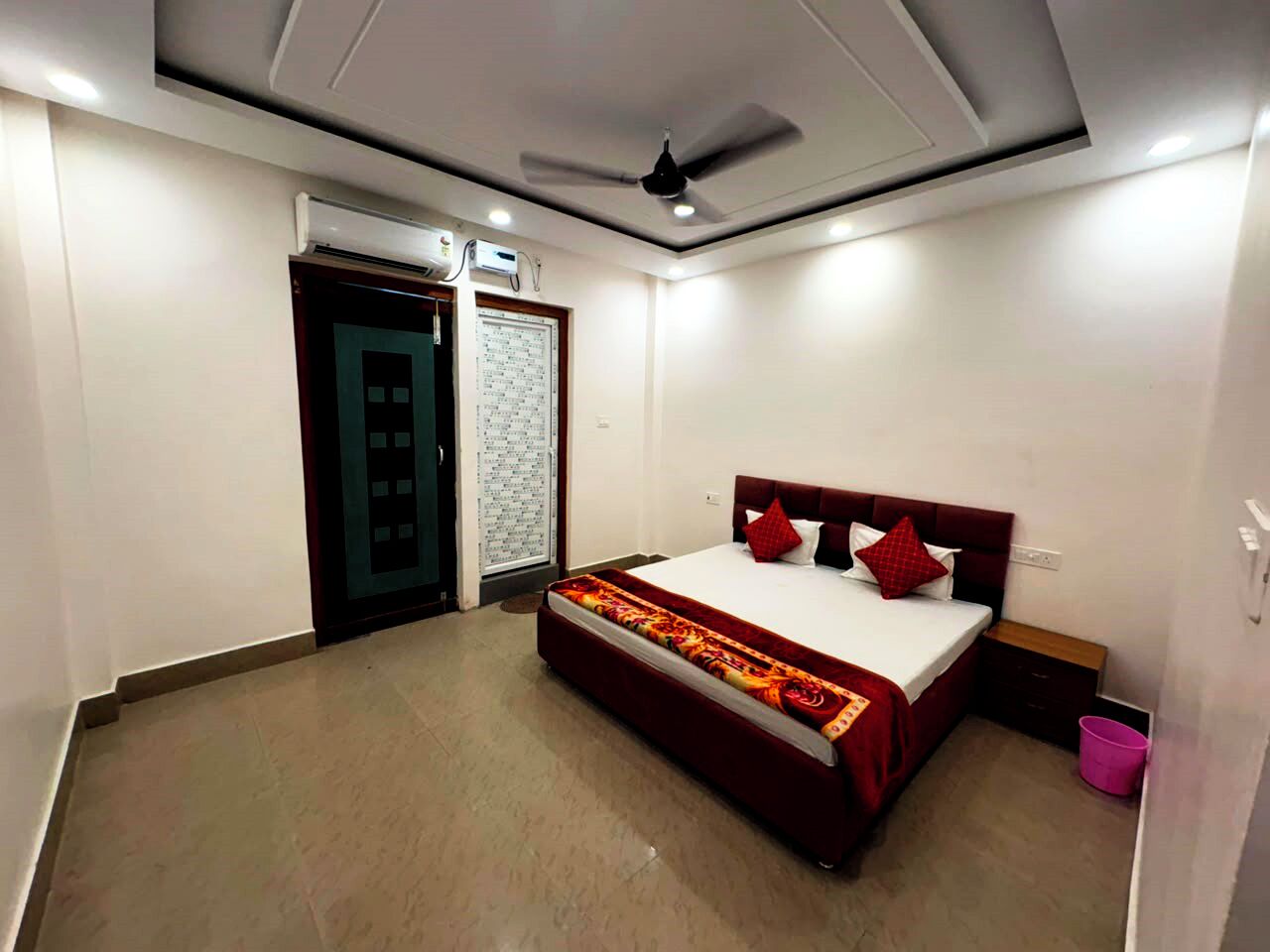 Quarto com cama, ventilador de teto, uma porta e ar-condicionado fixado na parede.