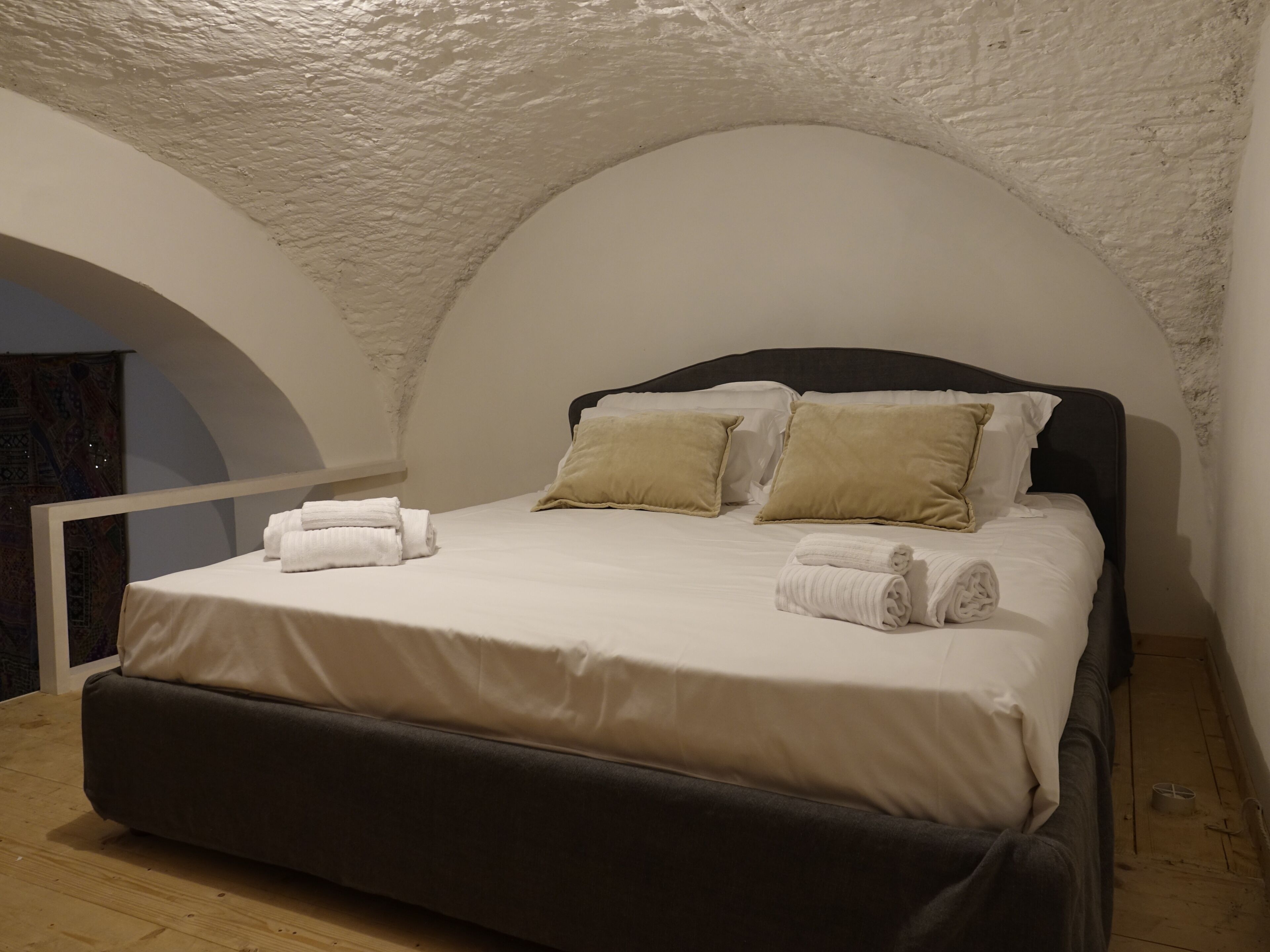 Quarto com cama, almofadas e toalhas.