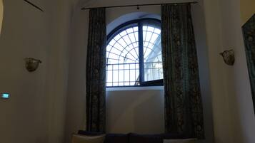 Um quarto com teto arredondado, janela com padrão de grade e sofá com almofadas.