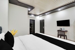 Quarto de hotel com cama, televisão de tela plana, escrivaninha com cadeira e ar condicionado.
