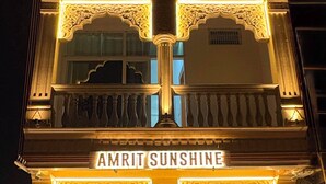 Um edifício com detalhes arquitetônicos elaborados e uma placa com a inscrição 'AMRIT SUNSHINE'.