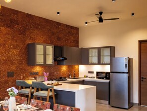 Uma cozinha moderna com ilha central, armários embutidos e geladeira de aço inoxidável.