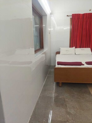 Quarto com uma cama, uma janela e cortina vermelha.