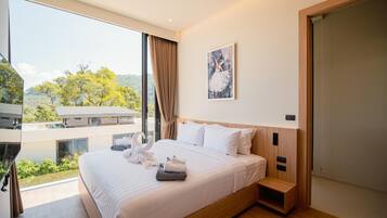 Quarto de hotel moderno com uma cama grande, um quadro na parede e vista para o exterior.