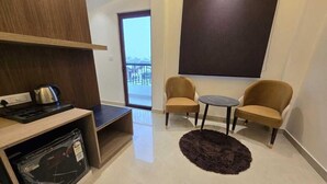 Uma sala de estar moderna com cozinha, duas poltronas, uma mesa pequena e vista através de uma porta de vidro.
