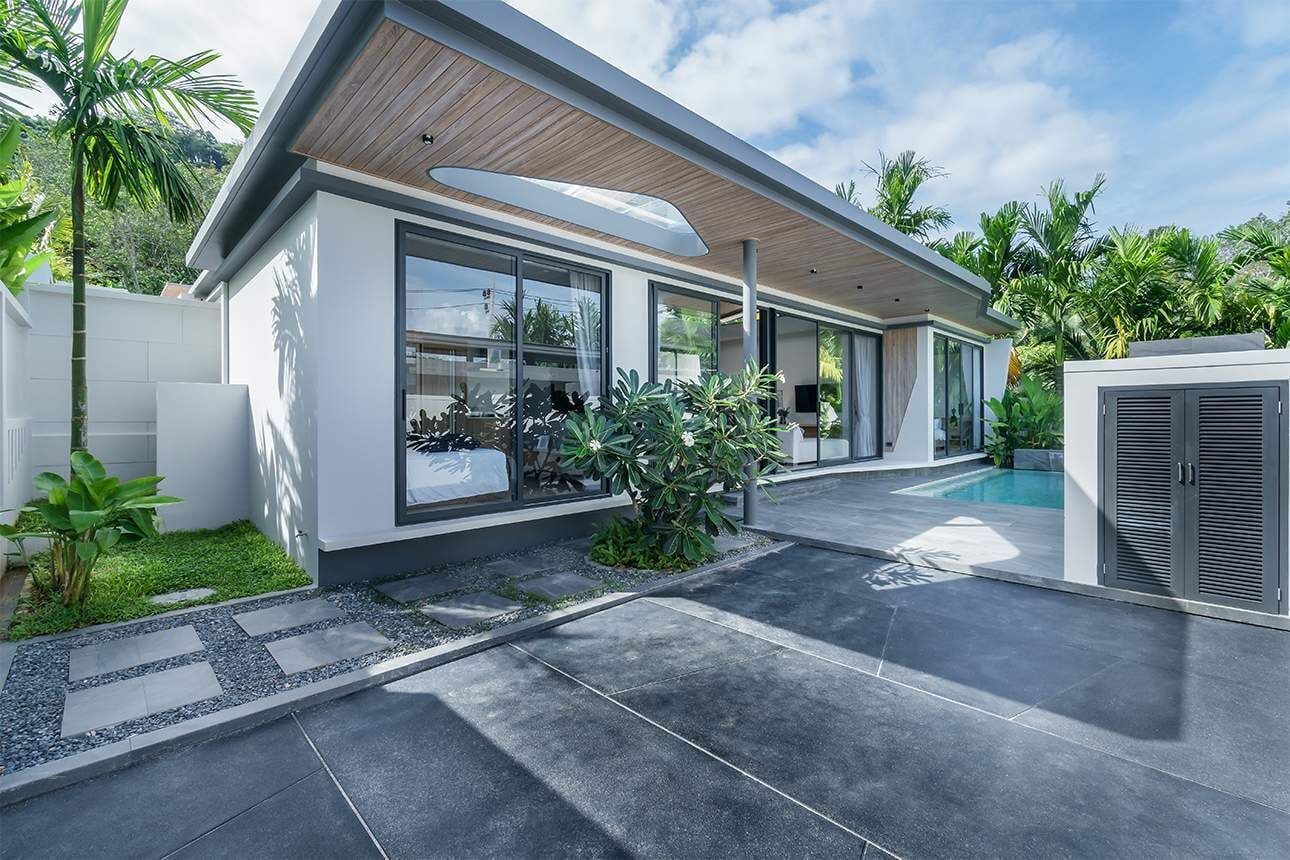 Uma casa moderna com piscina, grandes janelas e um espaço de varanda coberto.