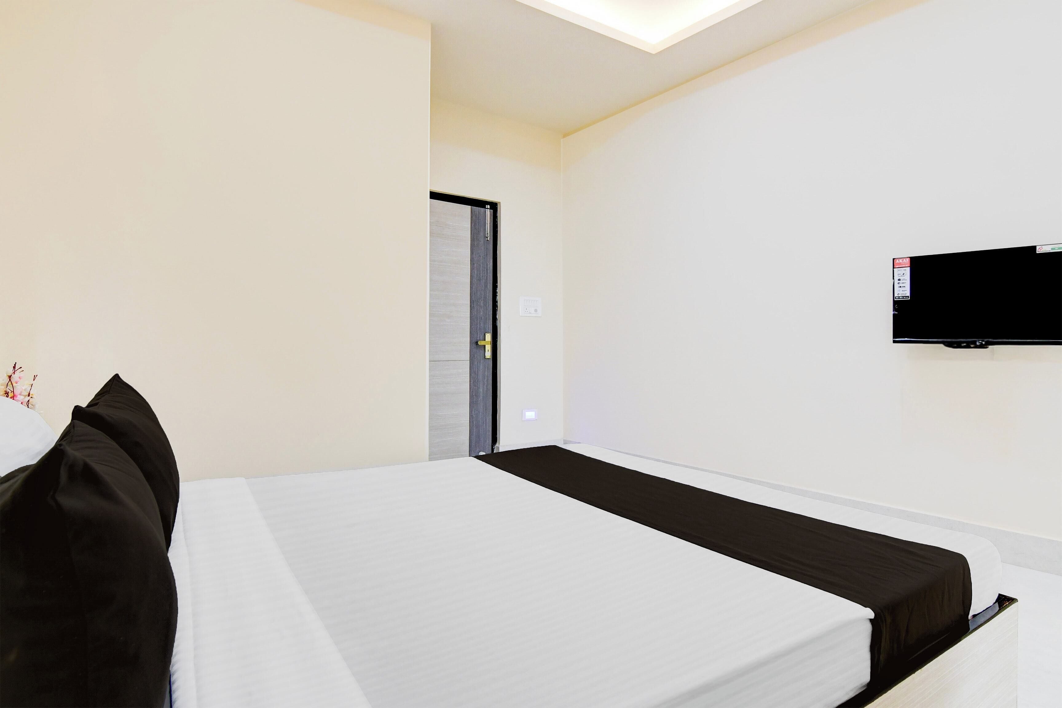 Quarto de hotel com uma cama, uma televisão de tela plana na parede e uma porta.