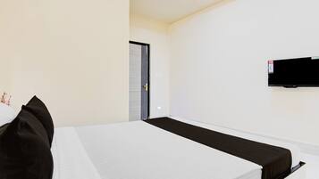 Quarto de hotel com uma cama, uma televisão de tela plana na parede e uma porta.