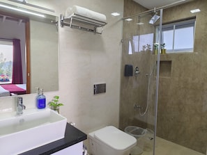Casa de banho com lavatório branco, sanita, cabine de duche em vidro e um porta-toalhas.